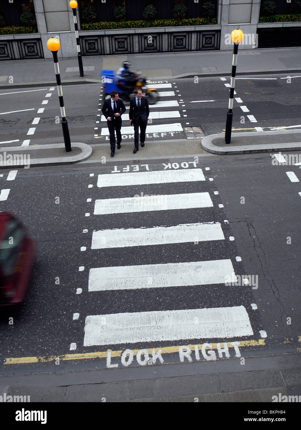 Commuters and motorcyclist crossing a zebra pelican crossing in London ...