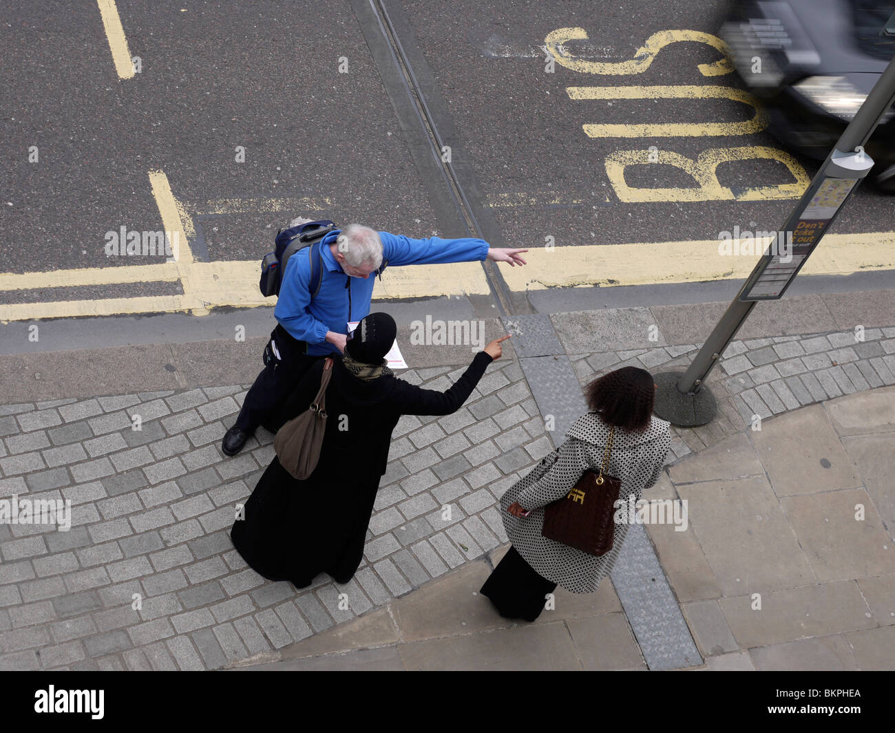 londoner guiding tourists, man pointing out directions at bus stop with ...