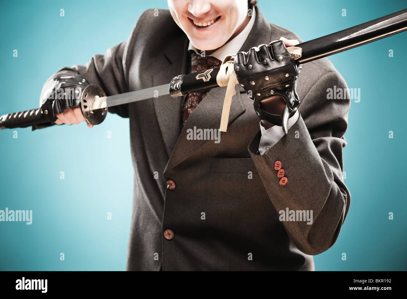 Young smiling businessman with sword in his arms ready to fight with ...