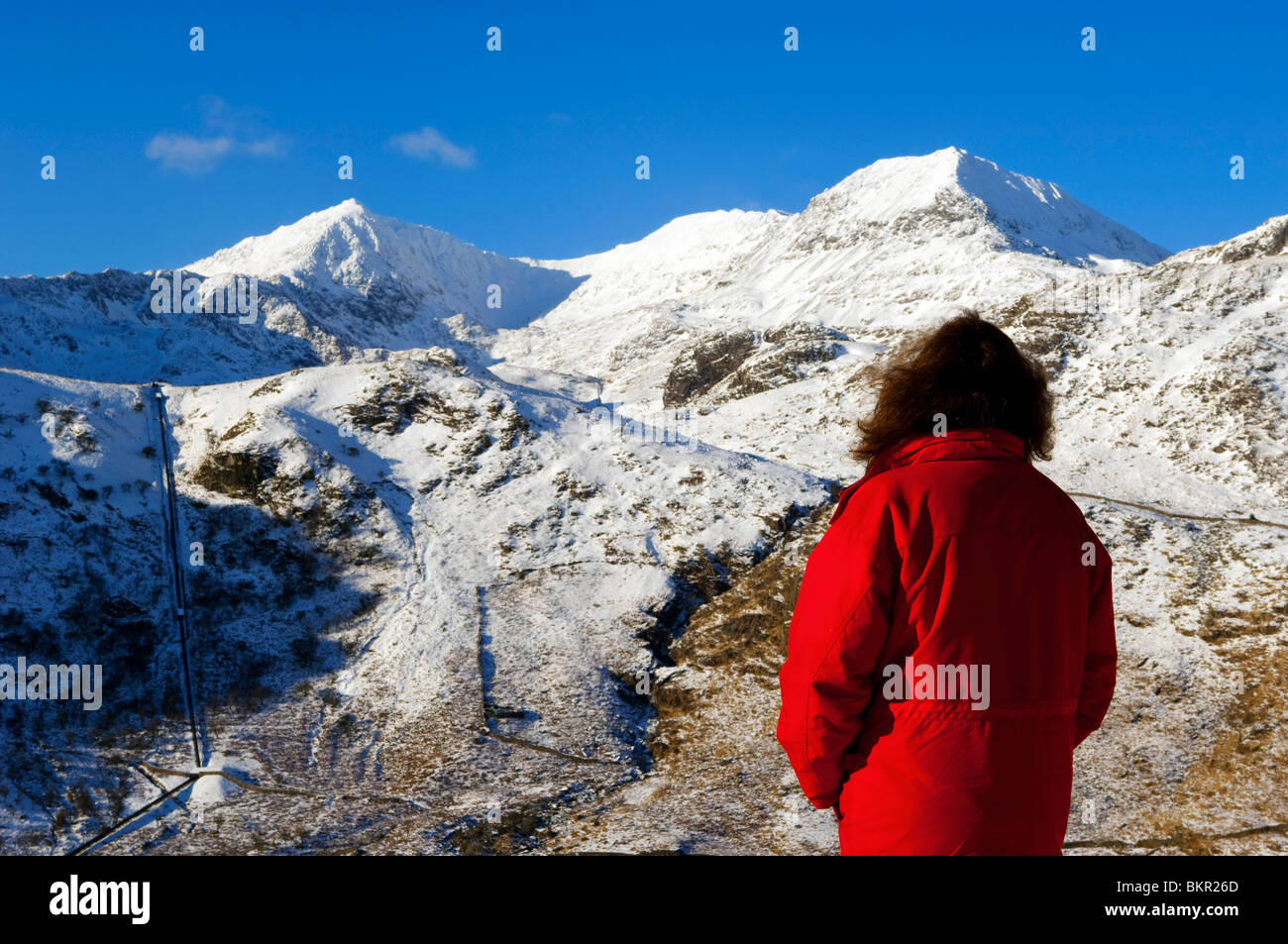 Wales, Gwynedd, Snowdonia. A walker looks westwards to the snow covered ...