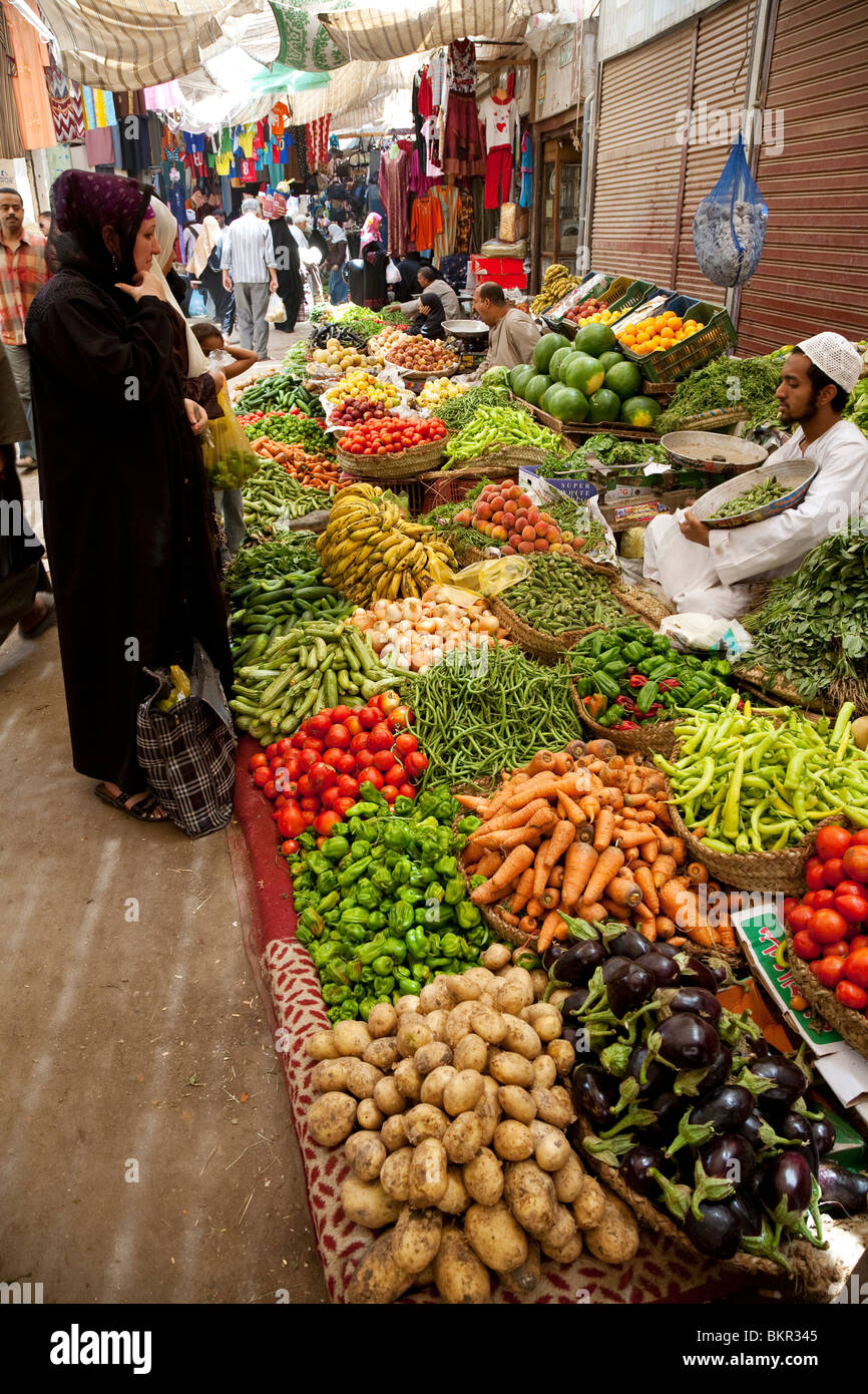 Egypt, Luxor. A woman buys fresh fruit and vegetables at a souq in ...