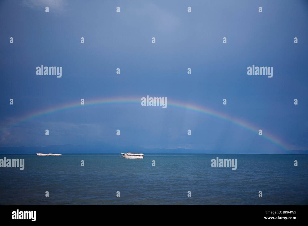 Malawi, Monkey Bay. A stunning rainbow appears over fishing boats on ...