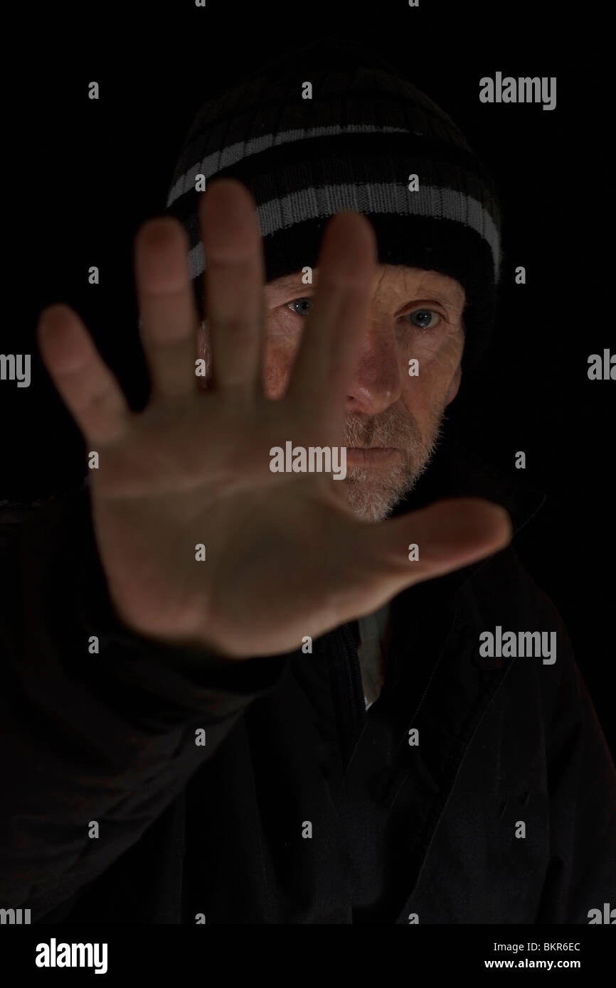 Man in black shielding his face with an outstretched hand. Isolated ...