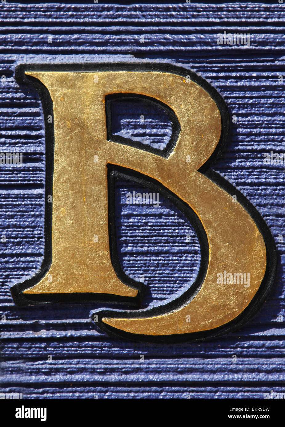 A decorative letter B over stucco wall outdoors with natural sunlight ...