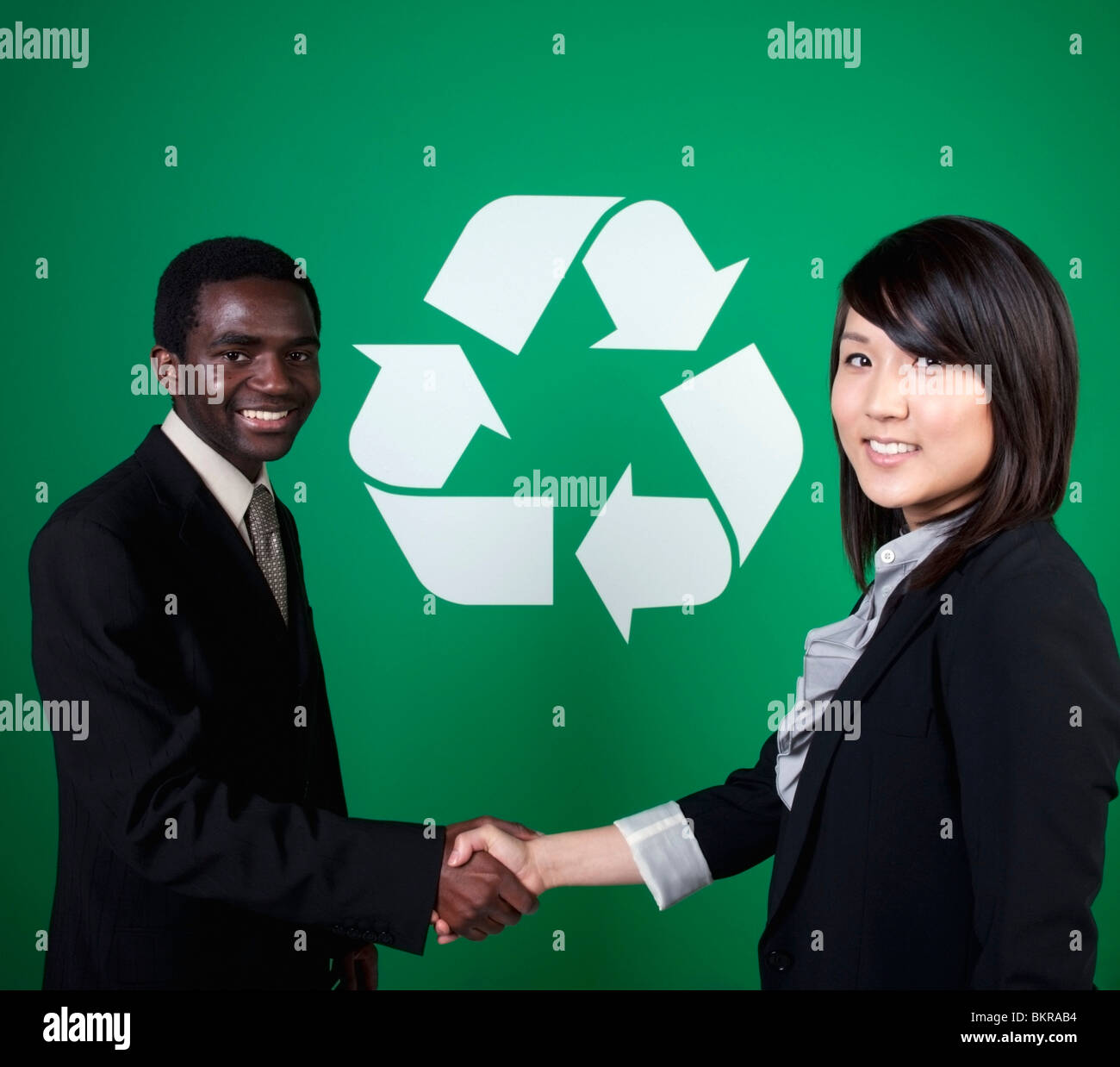 Two Business People Shaking Hands In Front Of A Recycle Symbol Stock ...