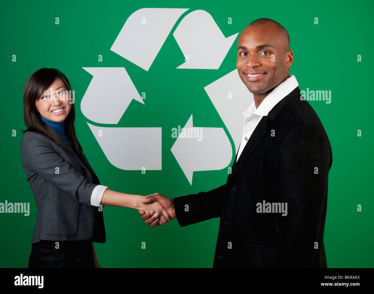 Two Business People Shaking Hands In Front Of A Recycle Symbol Stock ...