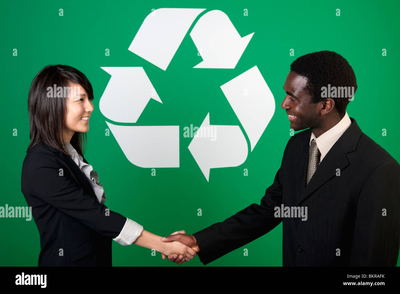 Two Business People Shaking Hands In Front Of A Recycle Symbol Stock ...