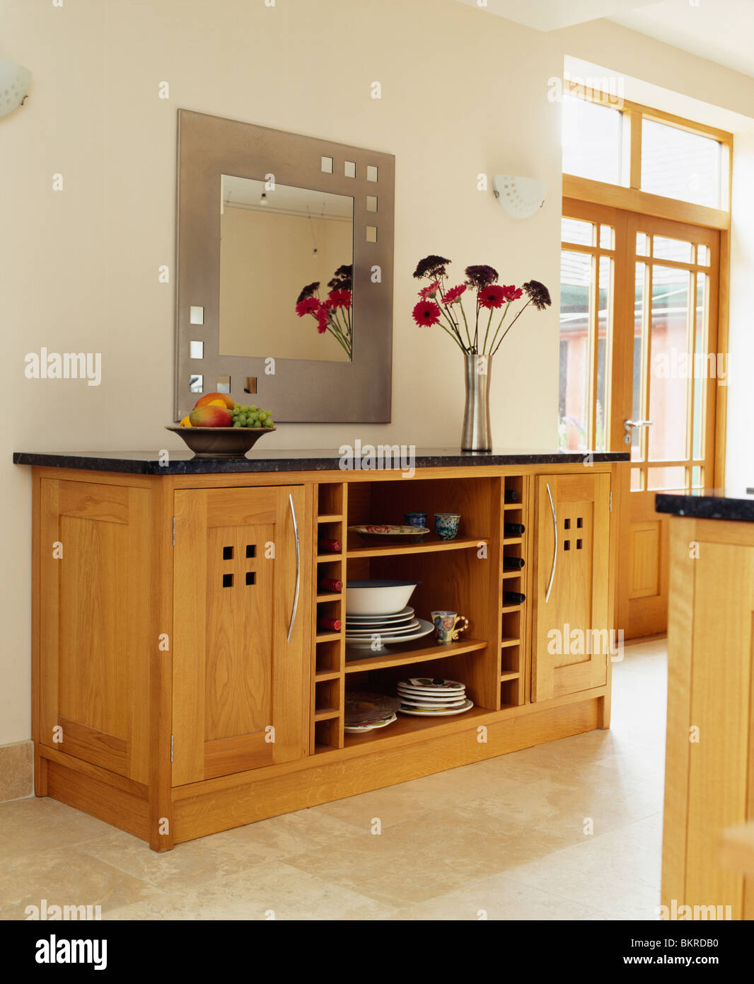 Metal-framed mirror above fitted oak storage and shelving unit in ...