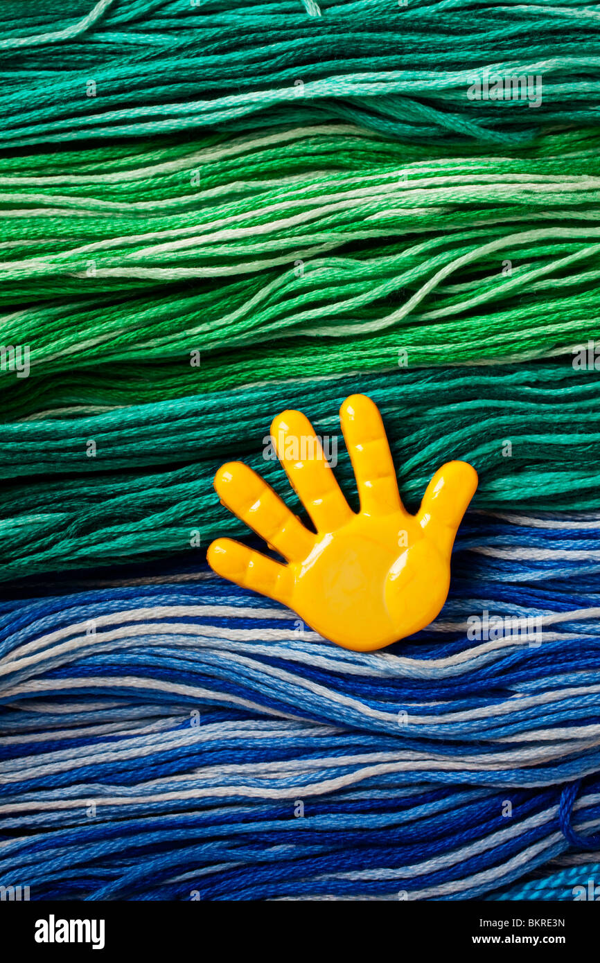 Yellow hand button on thread Stock Photo - Alamy
