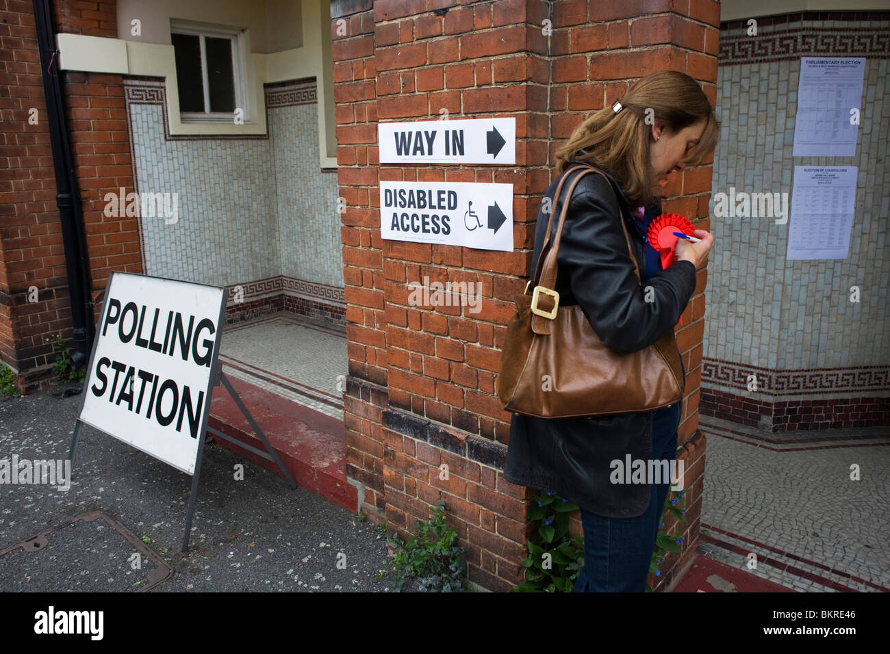 A teller attaches her red Labour Party rosette at the polling station ...