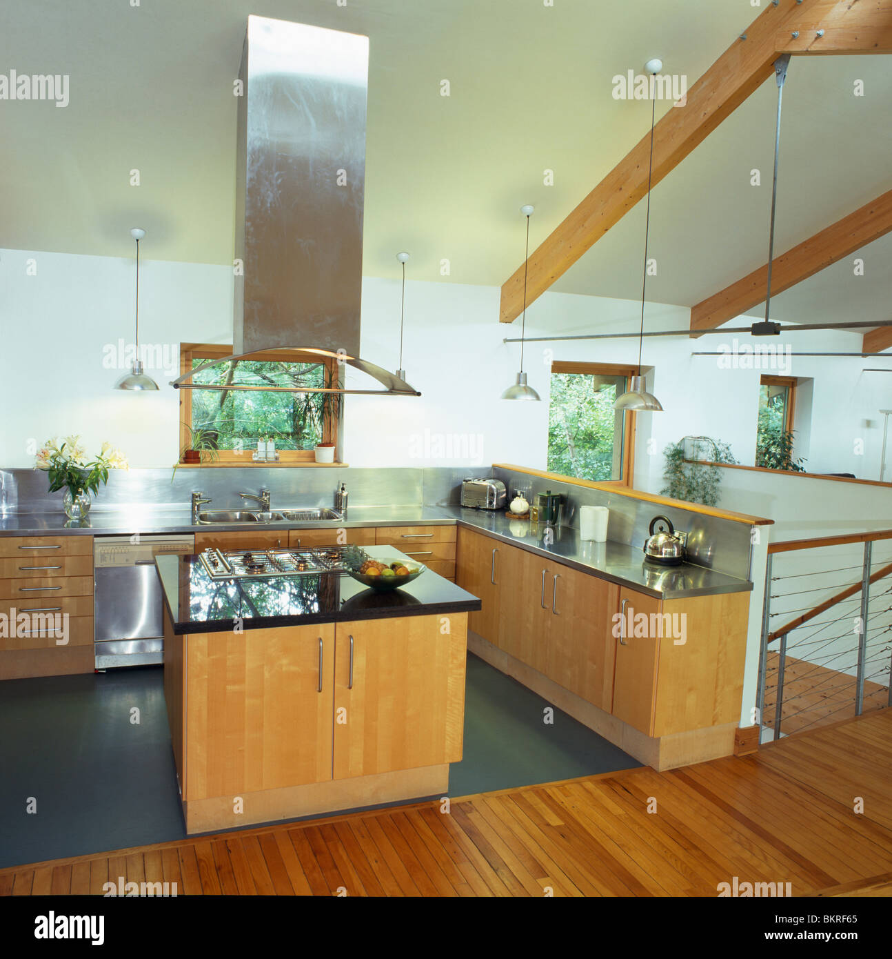 Large stainless steel extractor above hob in island unit in modern barn ...