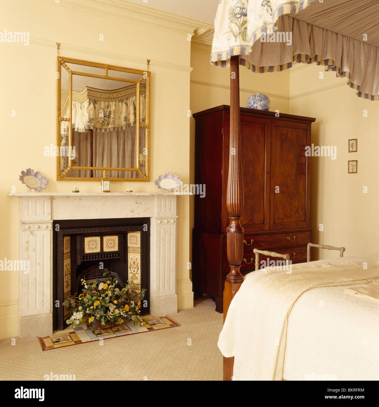 Antique mirror above marble fireplace in tradItional bedroom with four ...