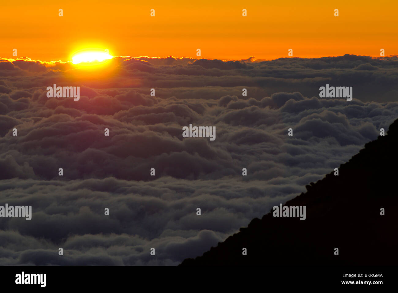The sun rises over clouds that hide the Pacific Ocean, from the summit ...