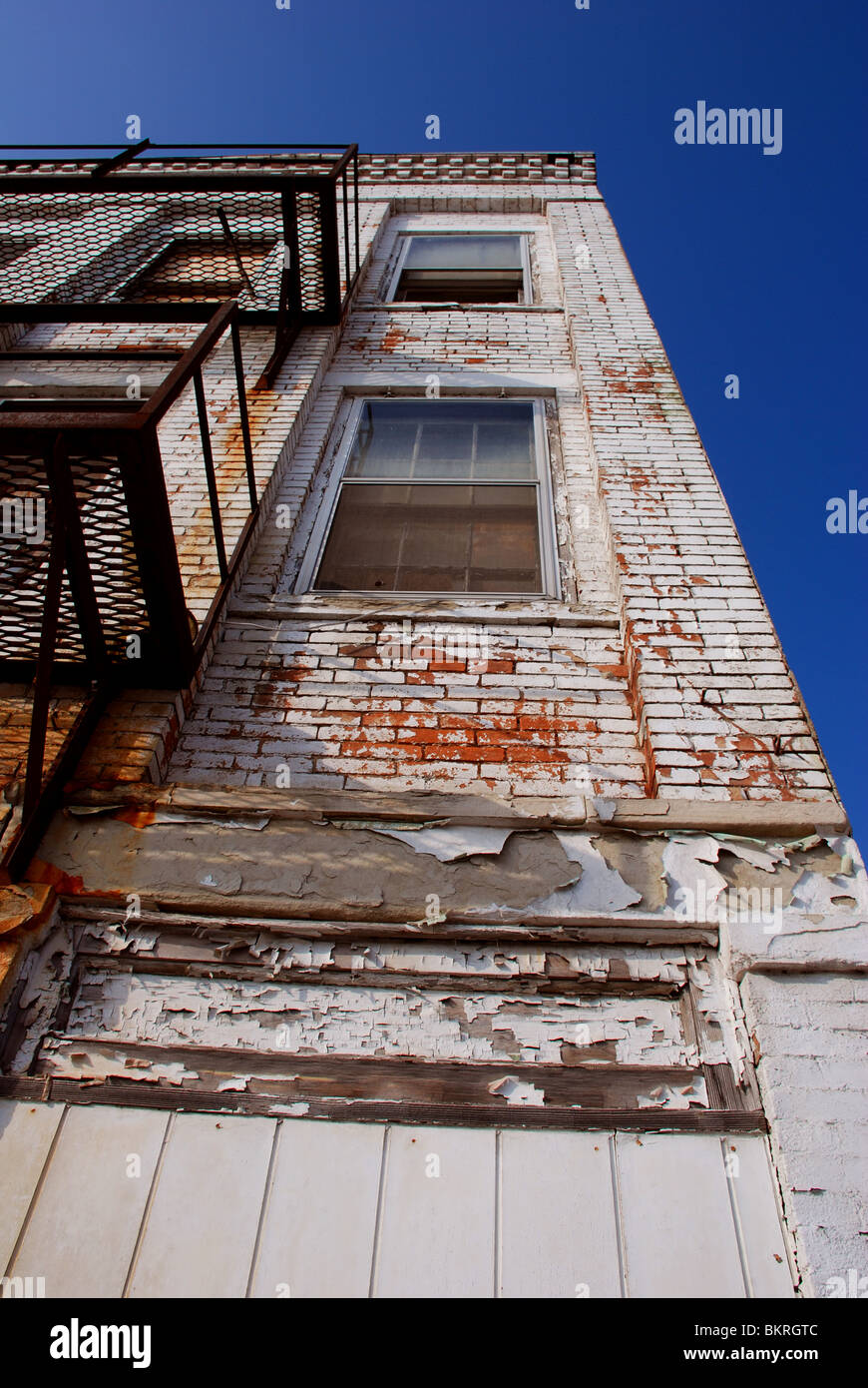Vertical view of an old abandoned building with rusted fire escape ...