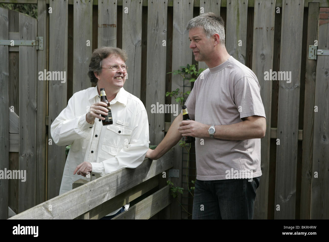 Neighbours talking over fence Stock Photo - Alamy
