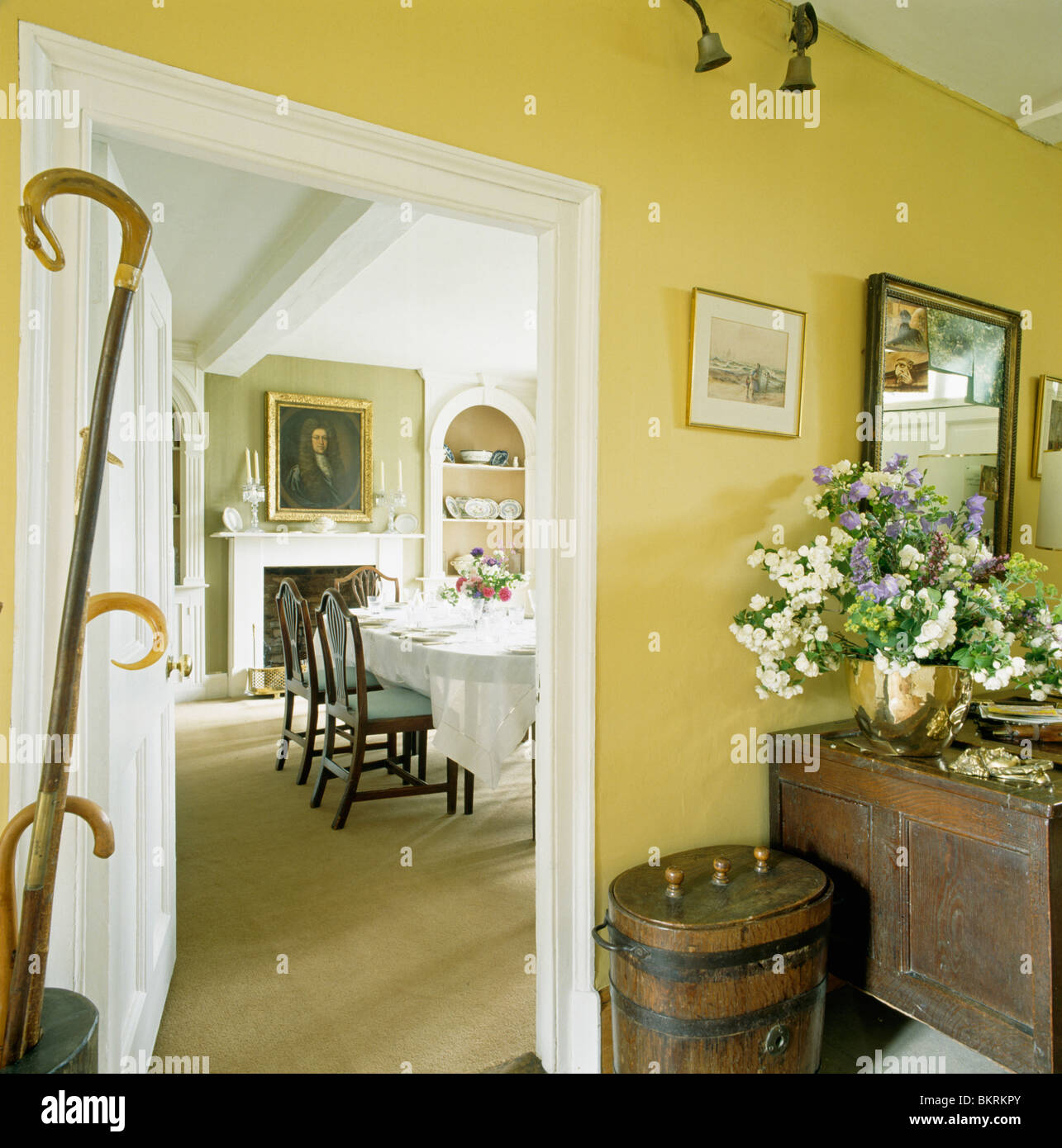 Antique chest in yellow cottage hall with door open to dining room with ...