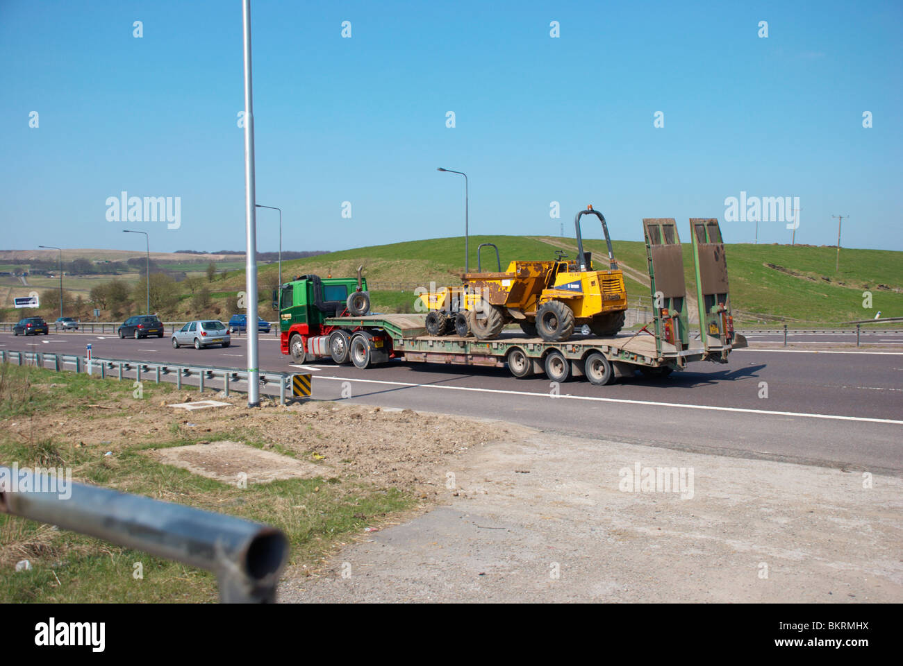 Low loader yellow with dumper truck on the M62 Stock Photo - Alamy