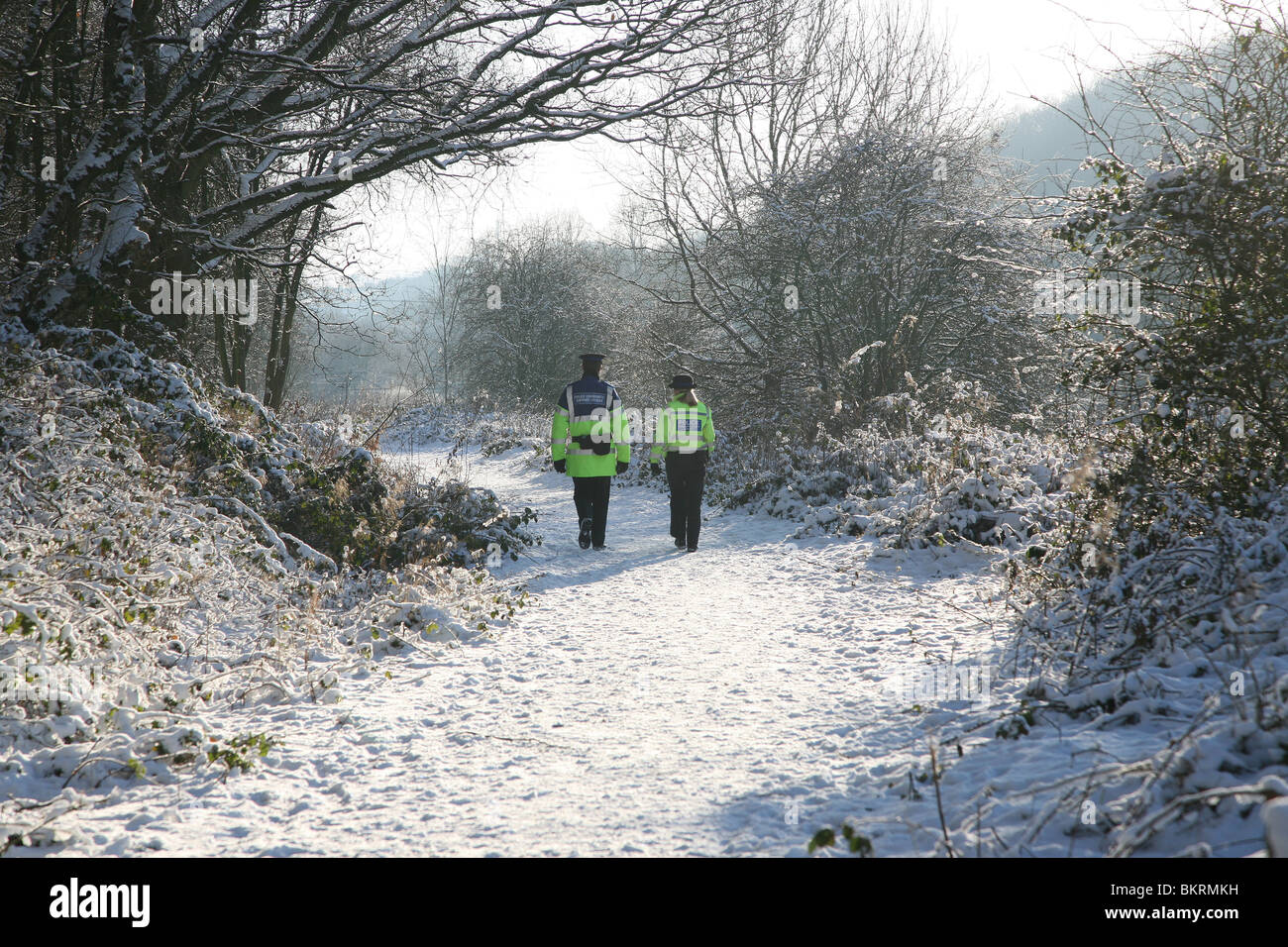 Two community police officers walking along a snow covered path at ...