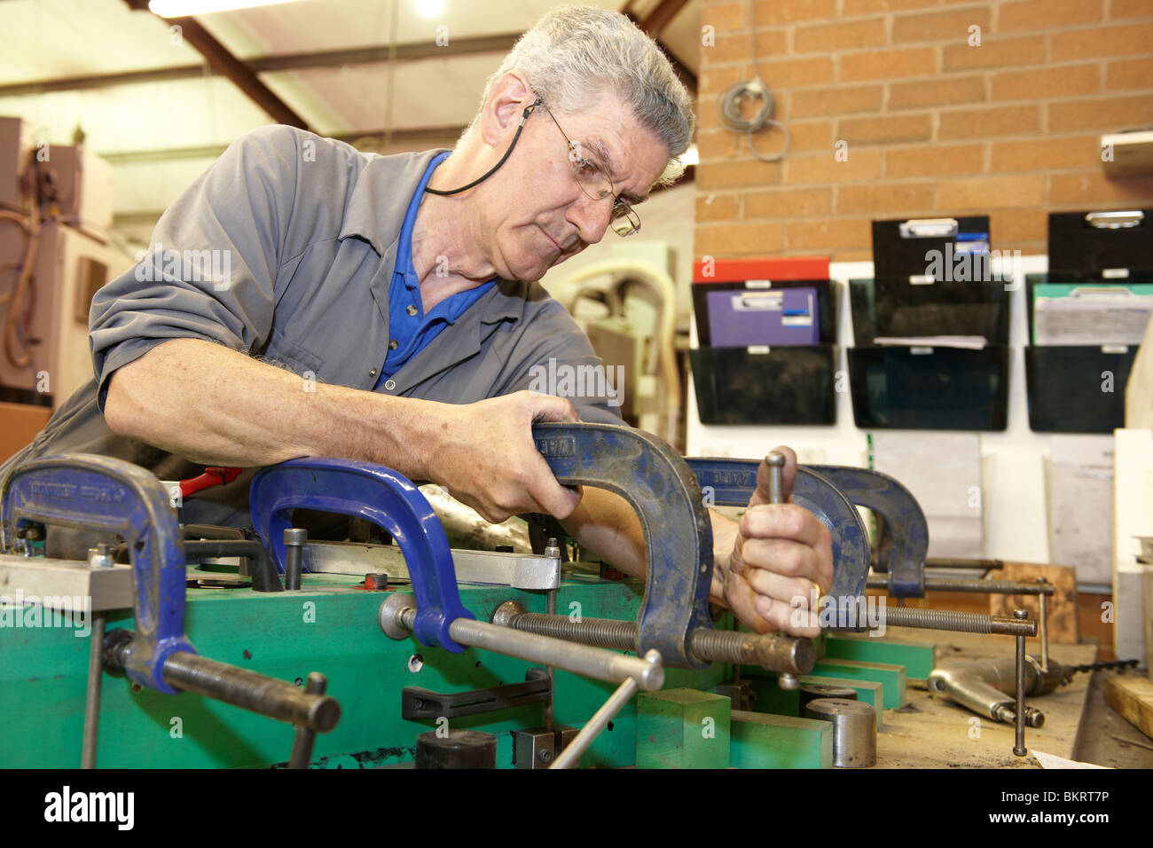 worker on factory floor tightening clamps to secure a machine Stock ...