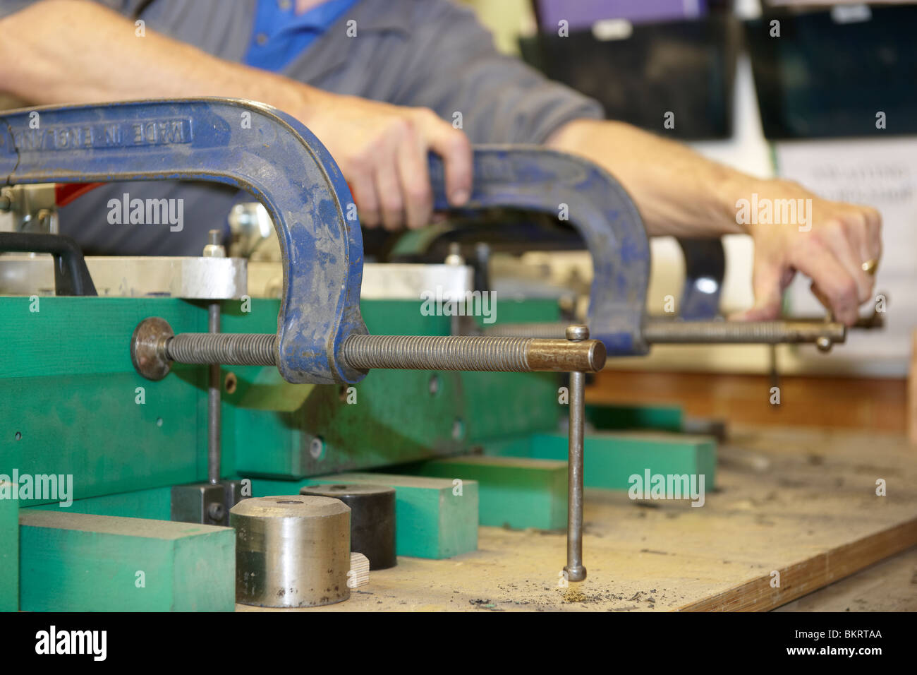 worker on factory floor tightening clamps to secure a machine Stock ...