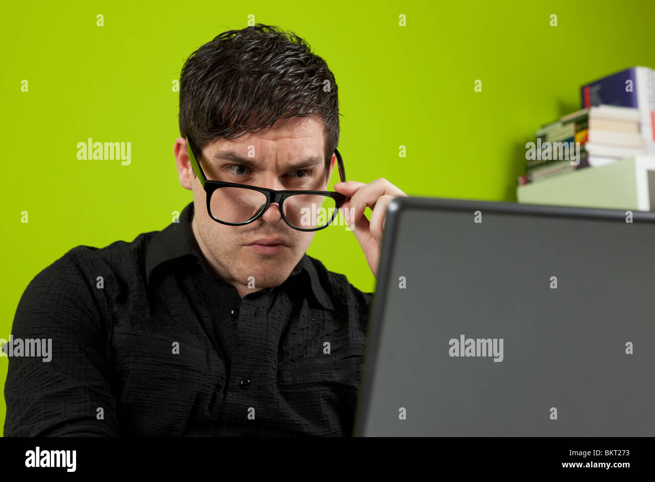 Young man squinting at the laptop Stock Photo - Alamy