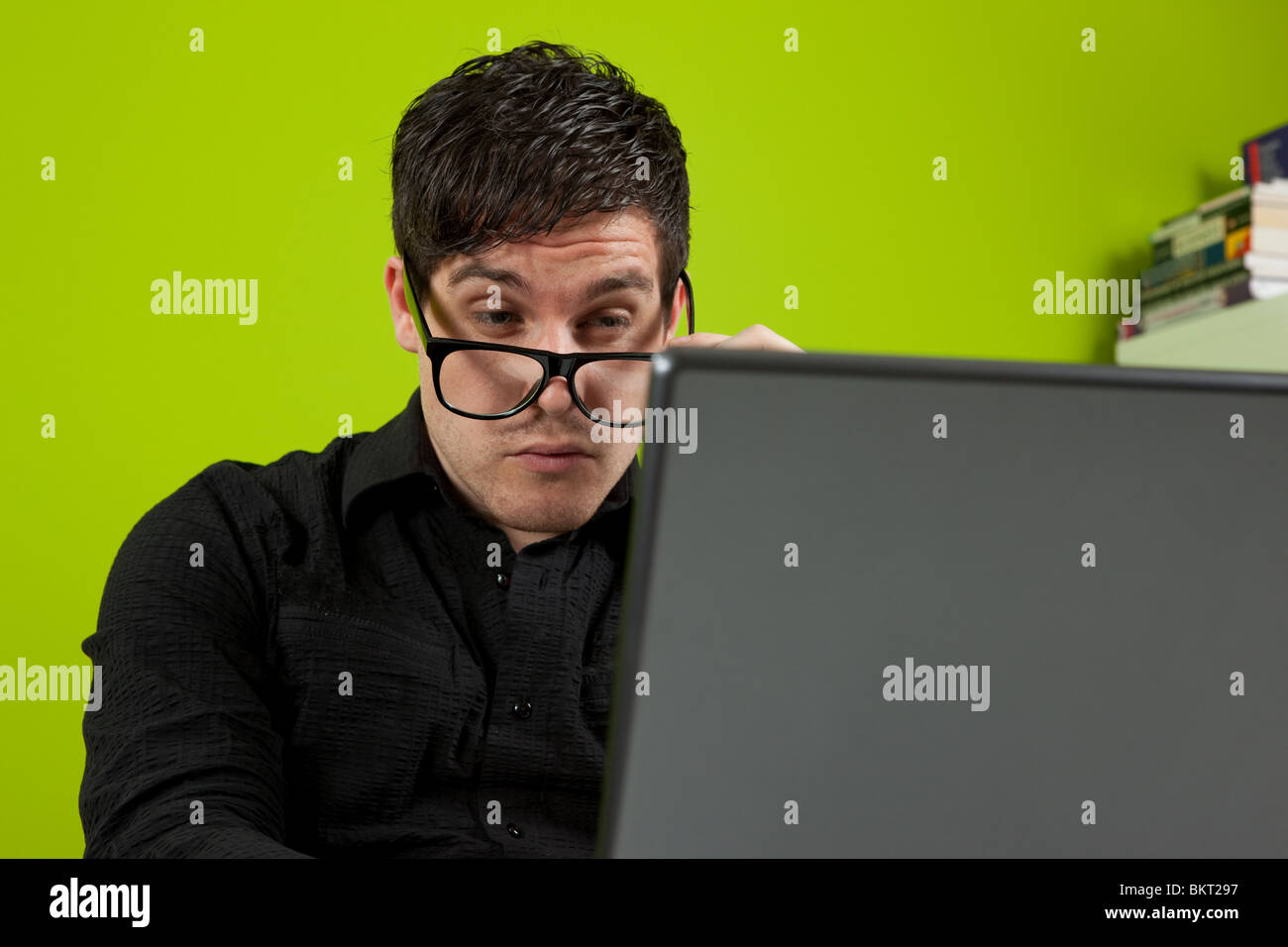 Young man squinting at the laptop Stock Photo - Alamy