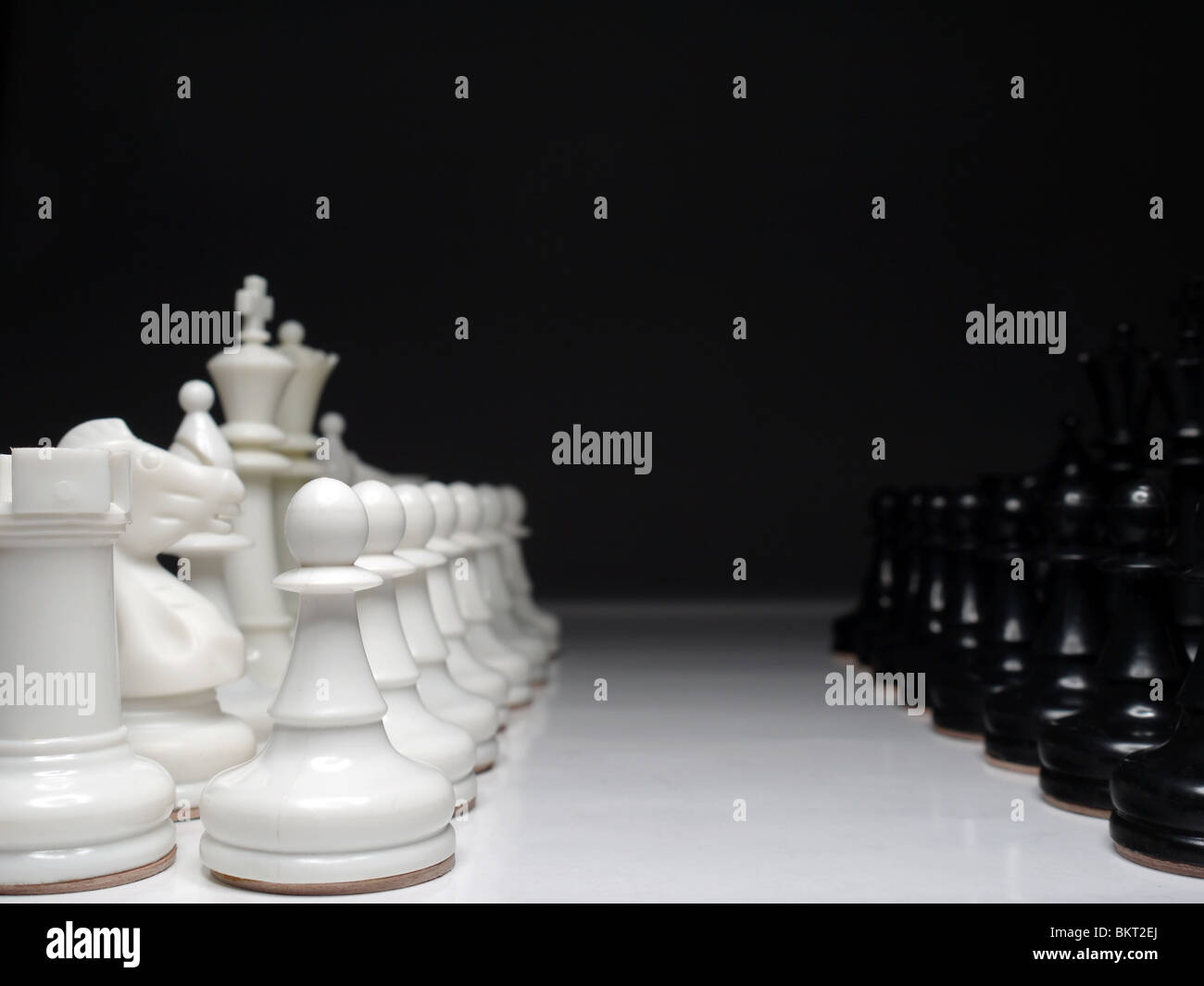 Rows of white and black set of chessmen standing face to face over ...