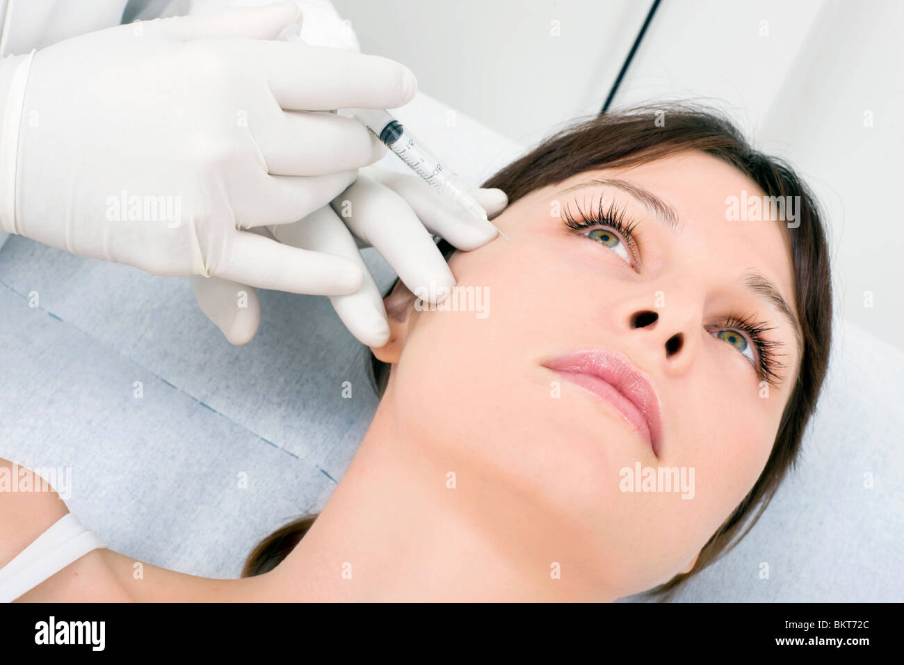 young caucasian woman receiving an injection of botox from a doctor ...