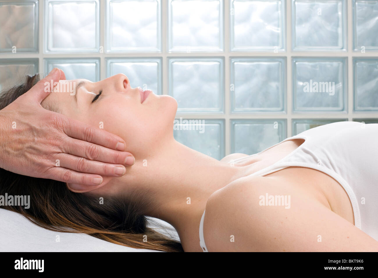 young caucasian woman lying down receiving head massage Stock Photo - Alamy