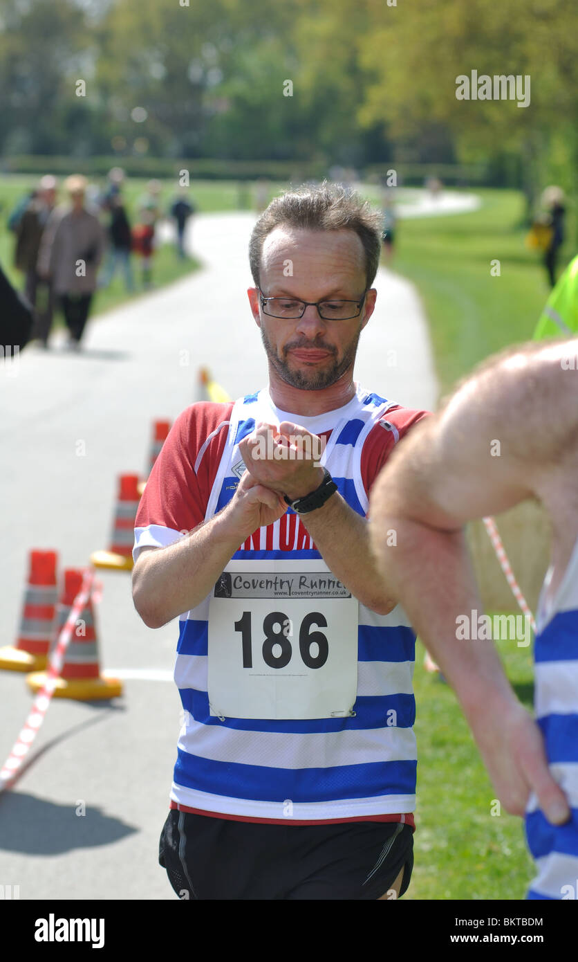A runner checking his stopwatch at the end of a road race Stock Photo ...