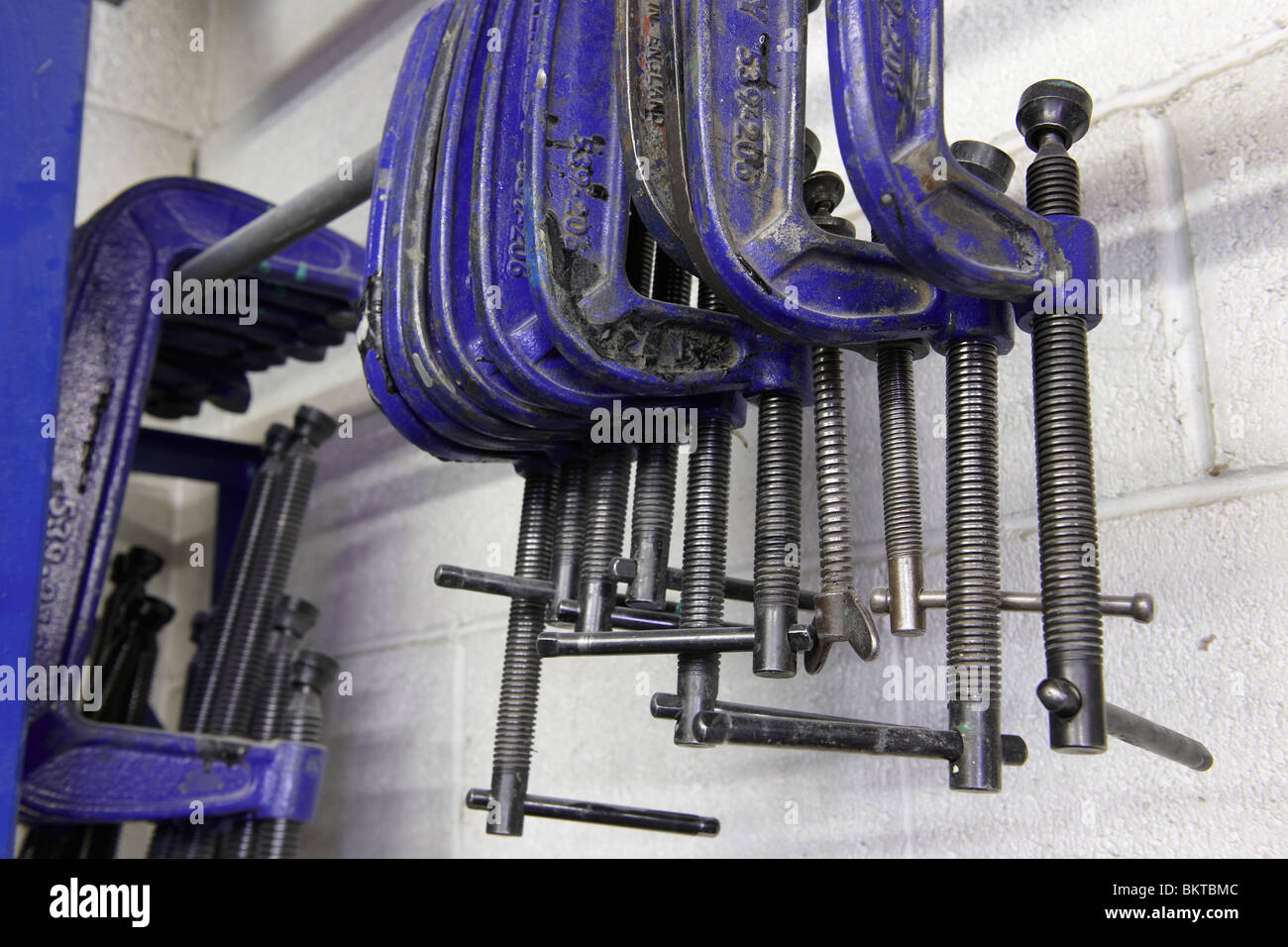 row of clamps hanging on a wall on factory floor Stock Photo - Alamy