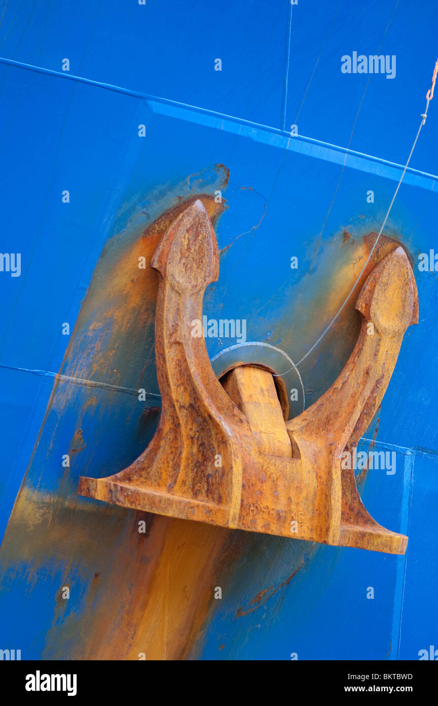 A rusty anchor provides contrast against a blue hull on an ocean going ...
