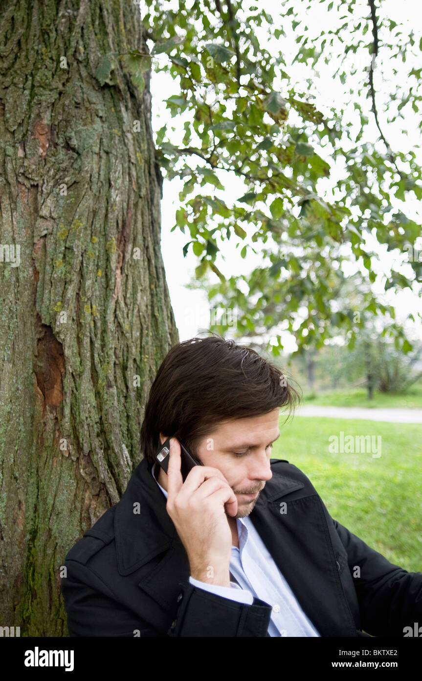 Man sitting under a tree talking on the phone Stock Photo - Alamy