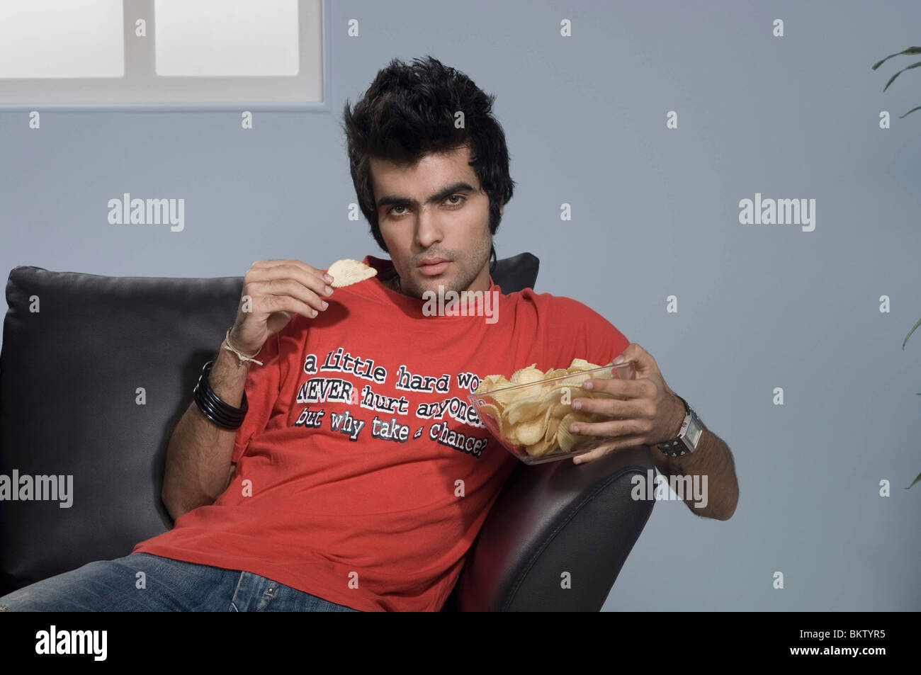 Young man eating potato chip, portrait Stock Photo - Alamy