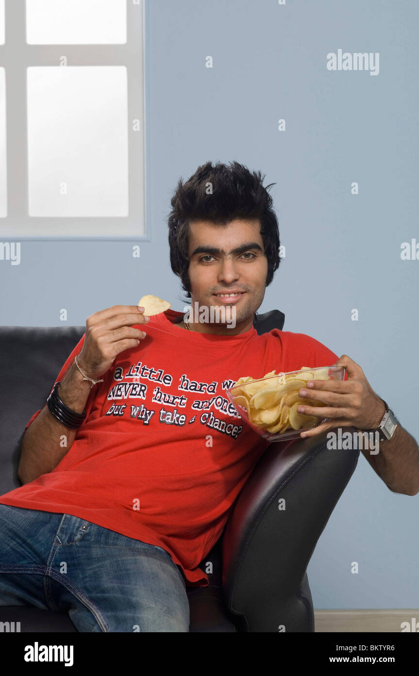 Young man holding potato chip, portrait Stock Photo - Alamy