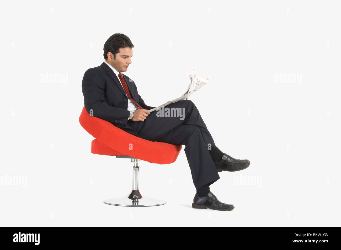 Young businessman reading newspaper, side view Stock Photo - Alamy