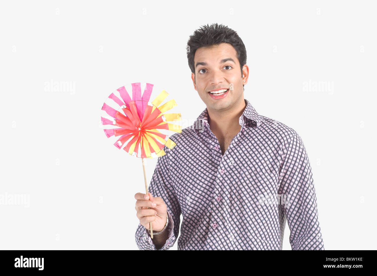 Young man holding pinwheel, smiling, portrait Stock Photo - Alamy