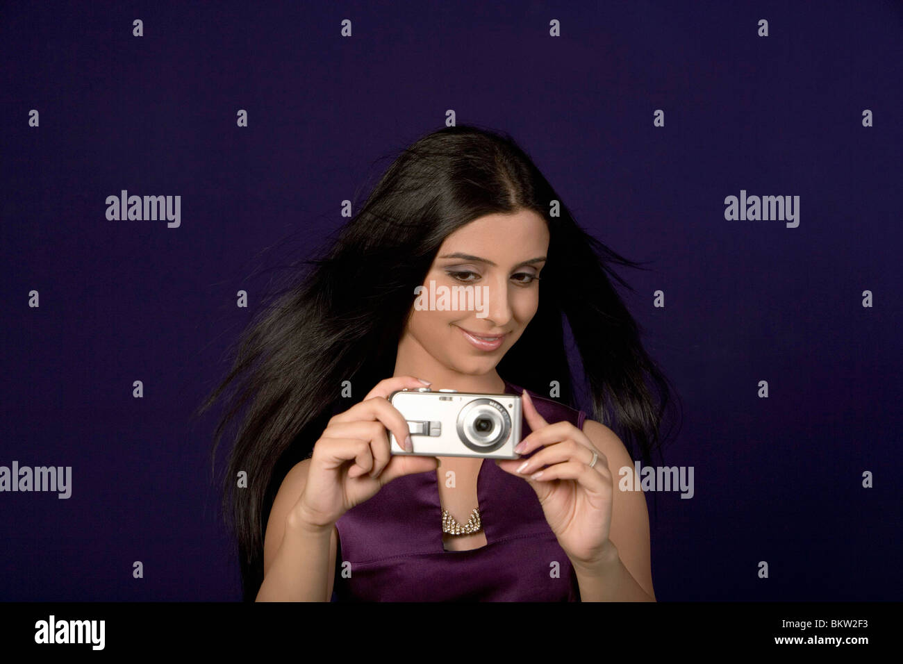 Young woman clicking photograph through digital camera, smiling Stock ...