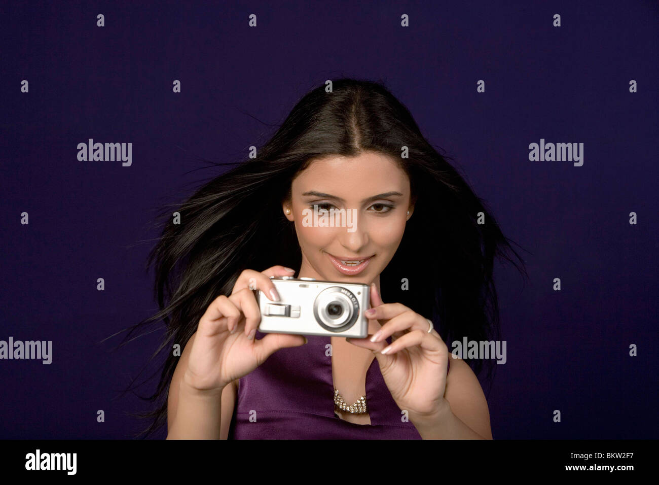 Young woman holding digital camera, smiling Stock Photo - Alamy