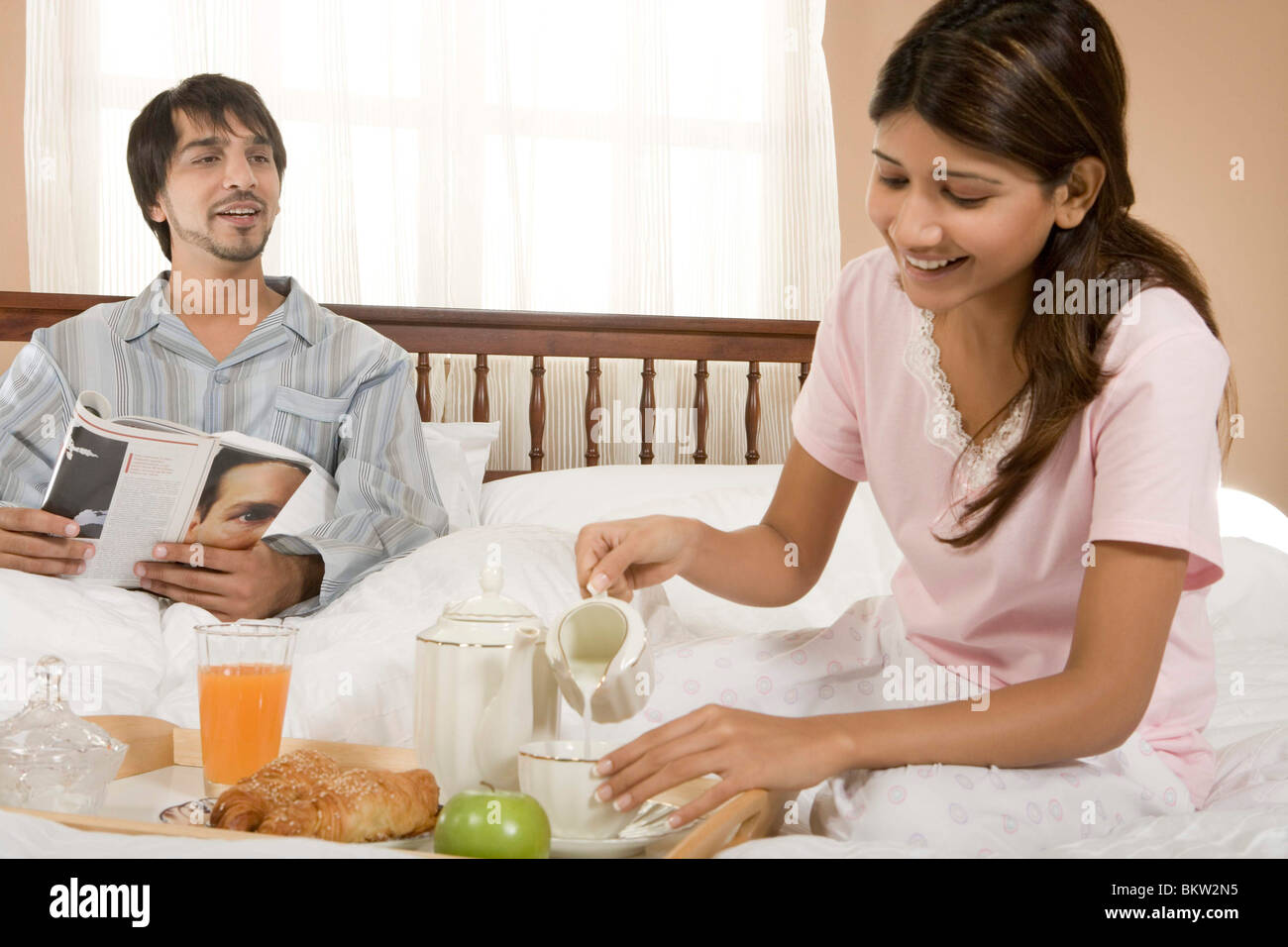 Young woman serving young man breakfast in bed Stock Photo - Alamy