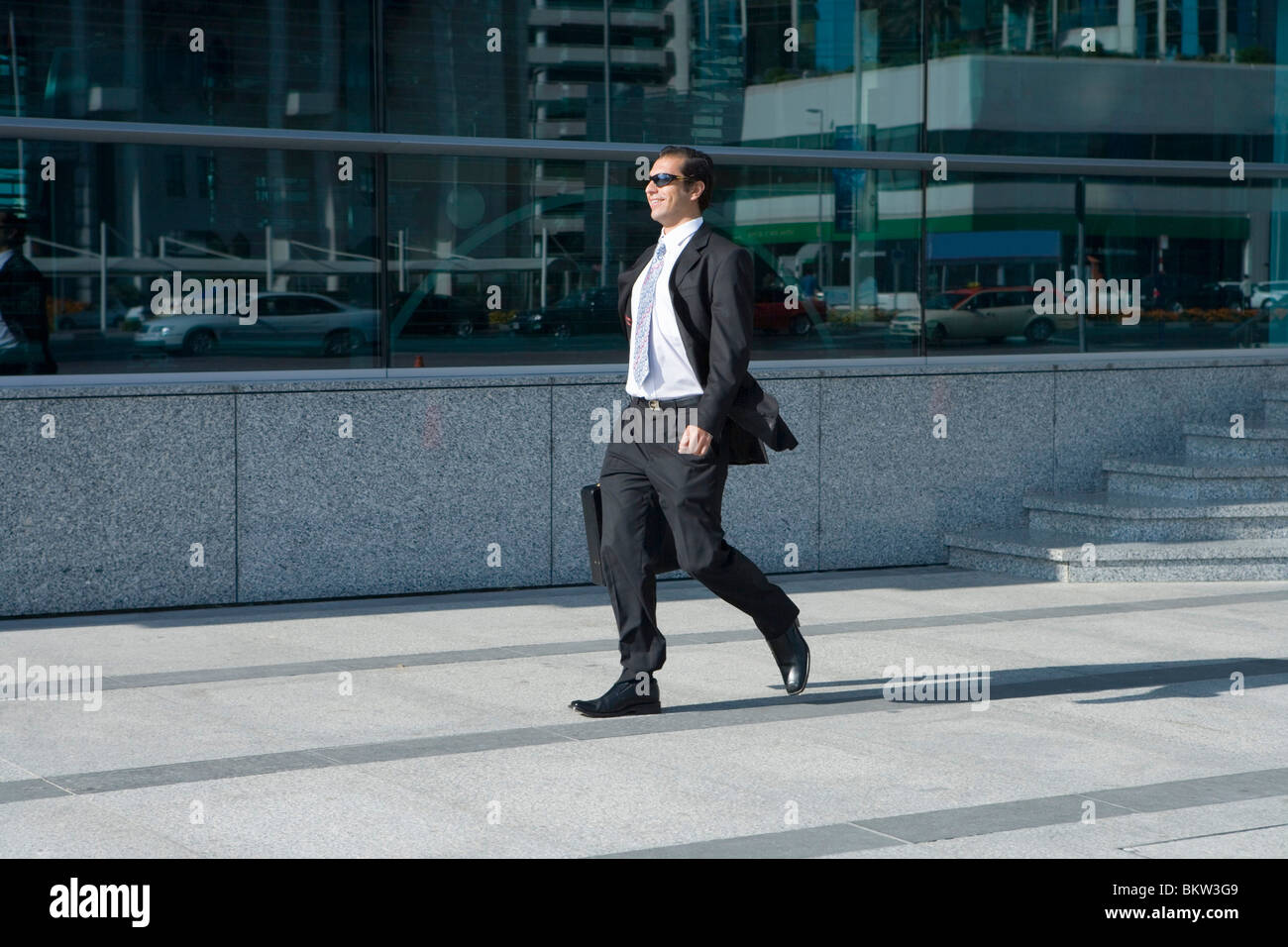 Businessman holding briefcase and walking by building Stock Photo - Alamy