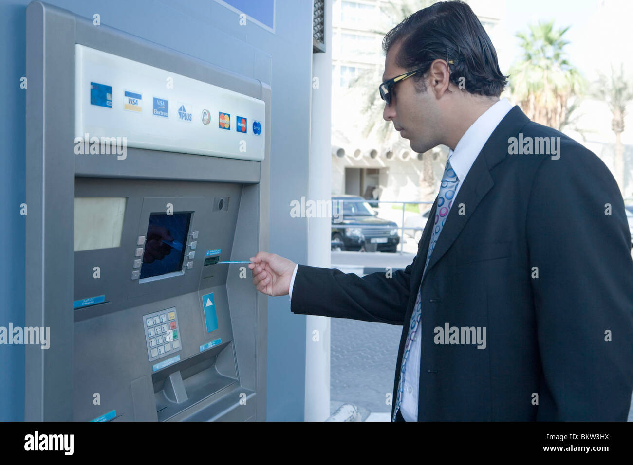 Businessman using an ATM machine Stock Photo - Alamy