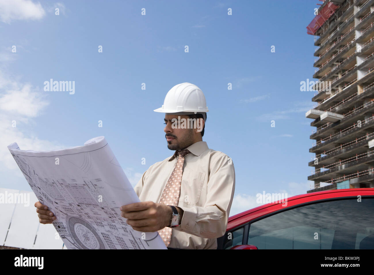 Architect looking at blueprint at construction site Stock Photo - Alamy