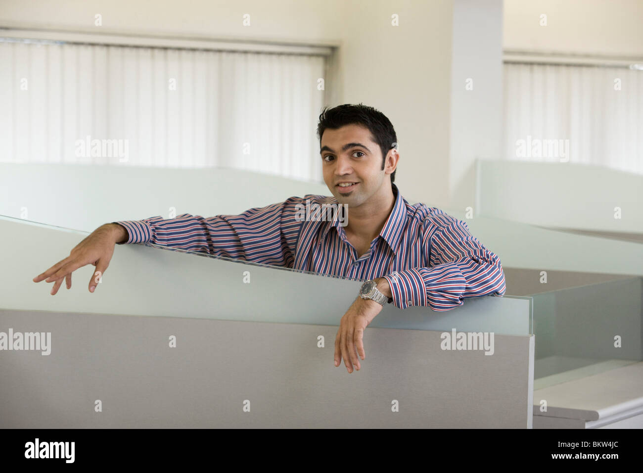 Businessman standing by the cubicle, smiling Stock Photo - Alamy