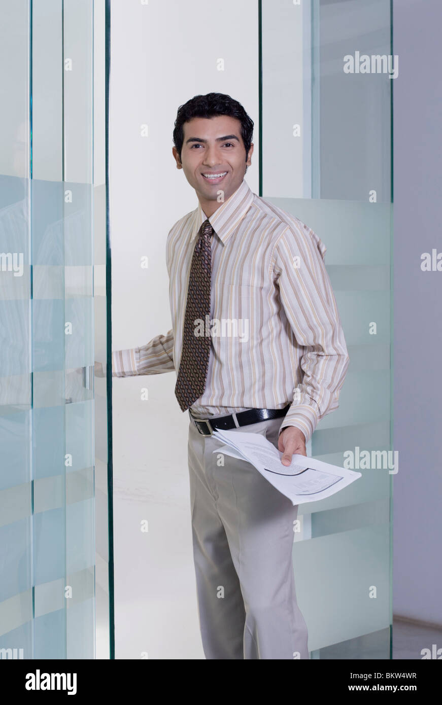 Businessman entering a room, holding a document Stock Photo - Alamy