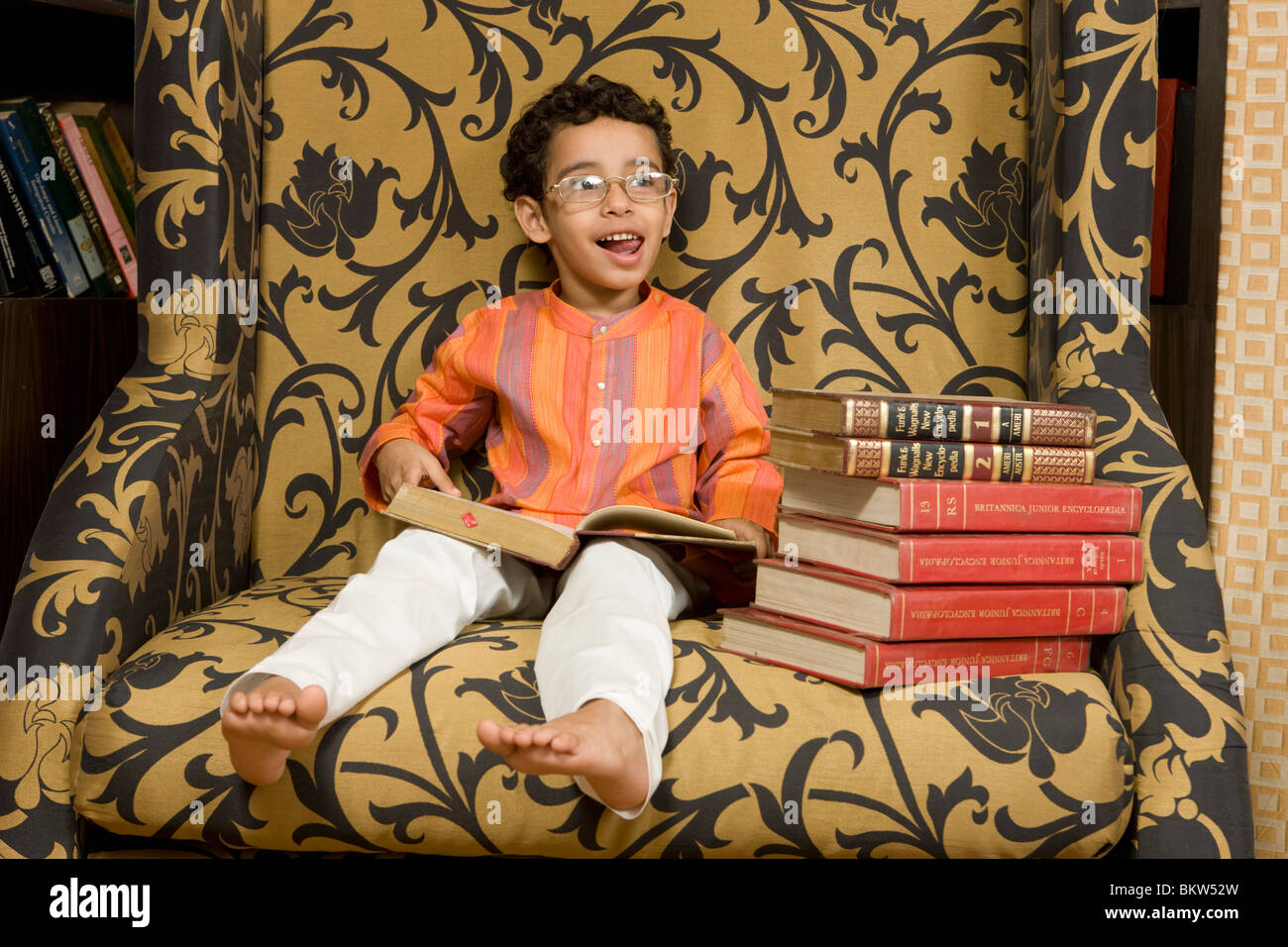Boy sitting in a couch, reading a book Stock Photo - Alamy