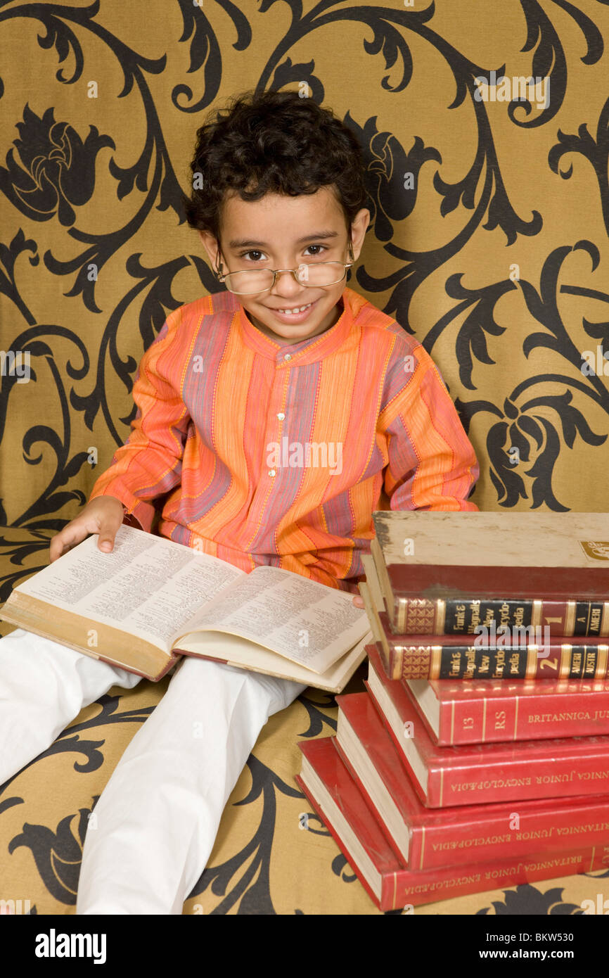 Boy sitting in a couch, reading a book Stock Photo - Alamy