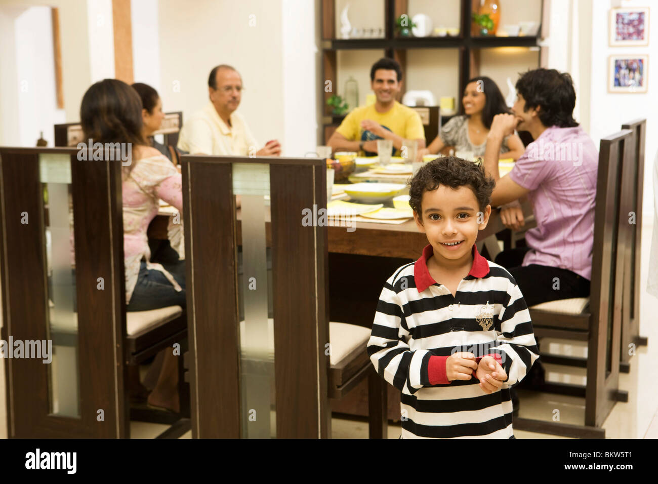 Boy smiling, background family in the dining room Stock Photo - Alamy