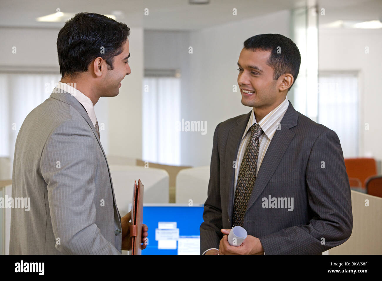 Two businessmen talking in the office, smiling Stock Photo - Alamy