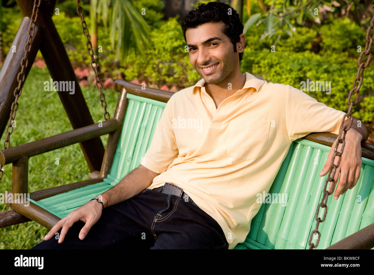 Man sitting on a swing in the garden Stock Photo - Alamy